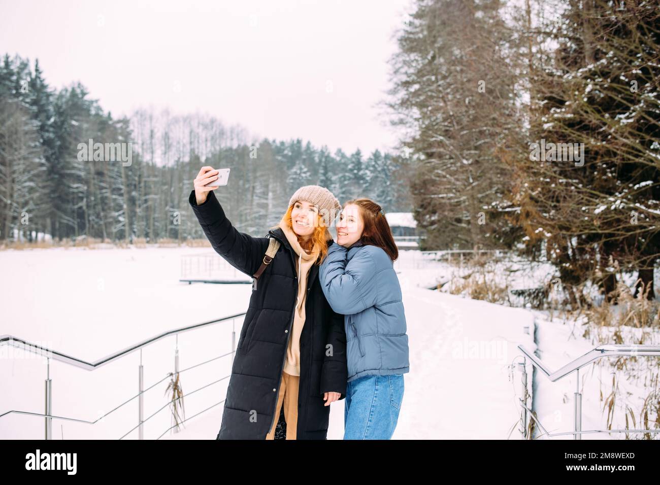 Two women friends in winter with a phone takes a selfie in winter Stock ...