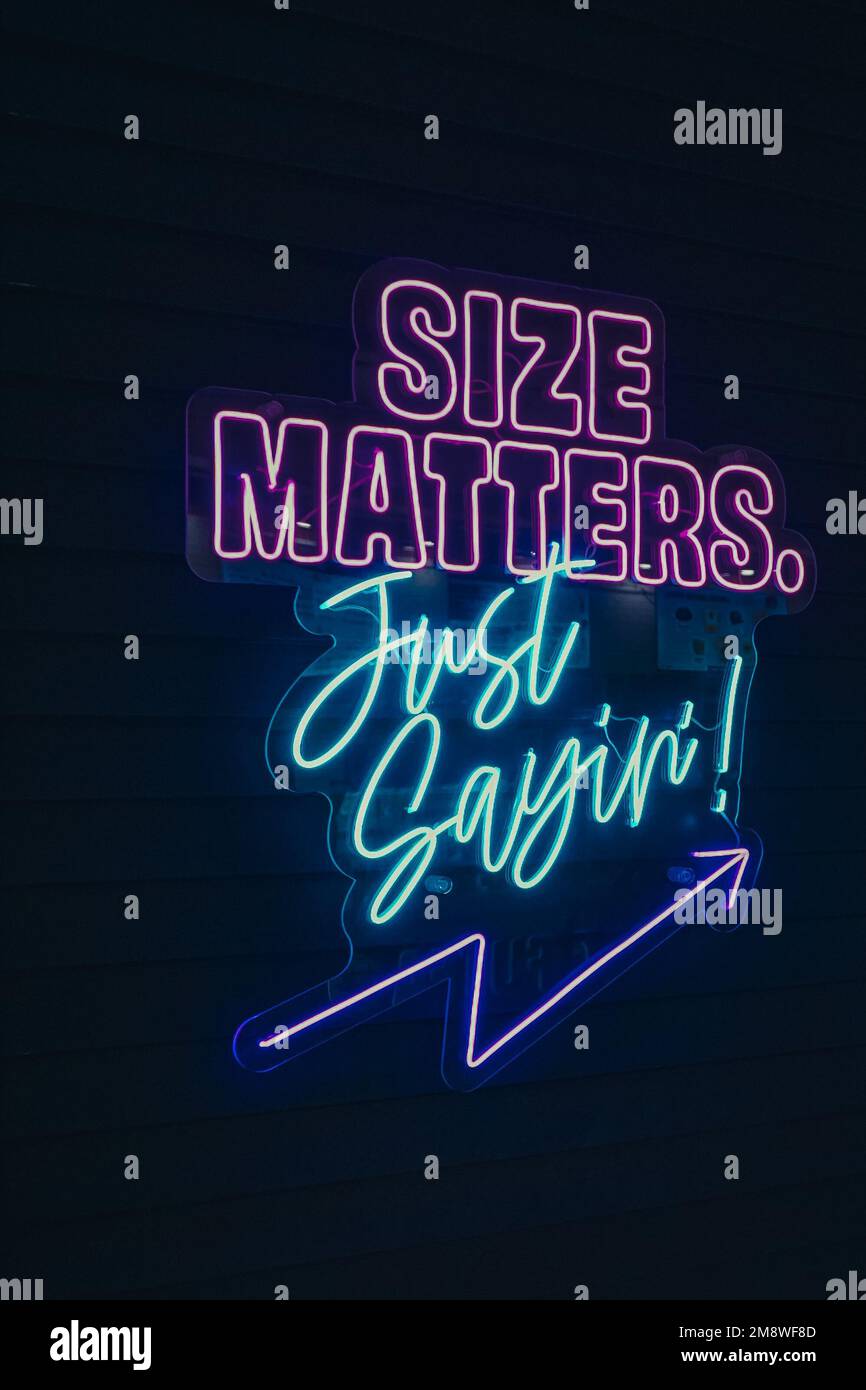 A vertical shot of a Size Matters Neon Sign Quote on a brick wall Stock ...