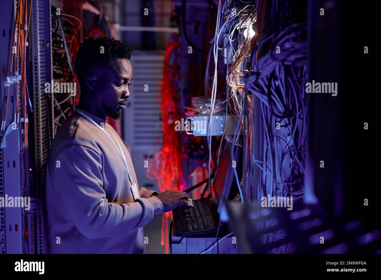 Side view portrait system administrator using computer in server room ...