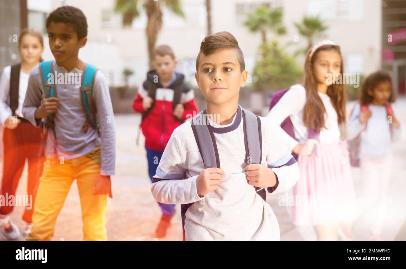Positive boy standing near school, children on background Stock Photo ...