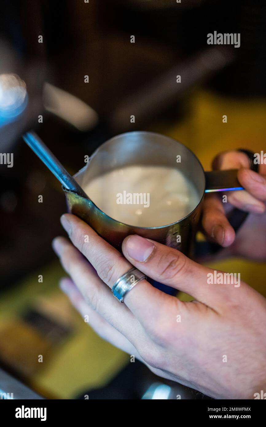Beating of milk in milk seller at the espresso steamer, while making a ...
