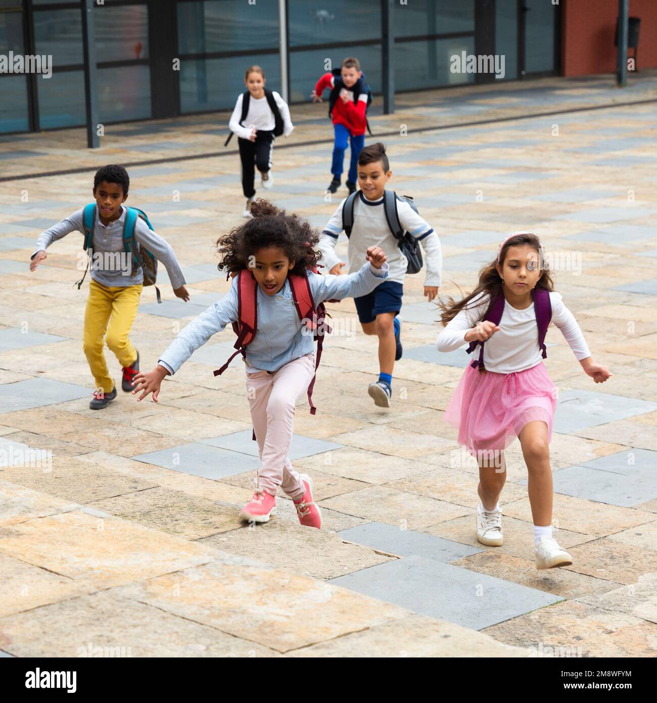 Tween boys and girls with school backpacks running in schoolyard Stock ...