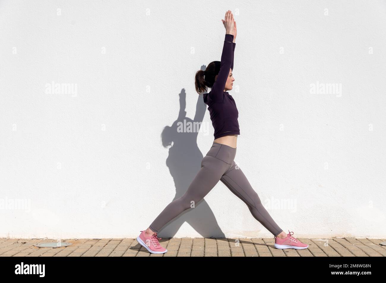 Sporty woman doing lunge exercise outside against a white wall Stock ...