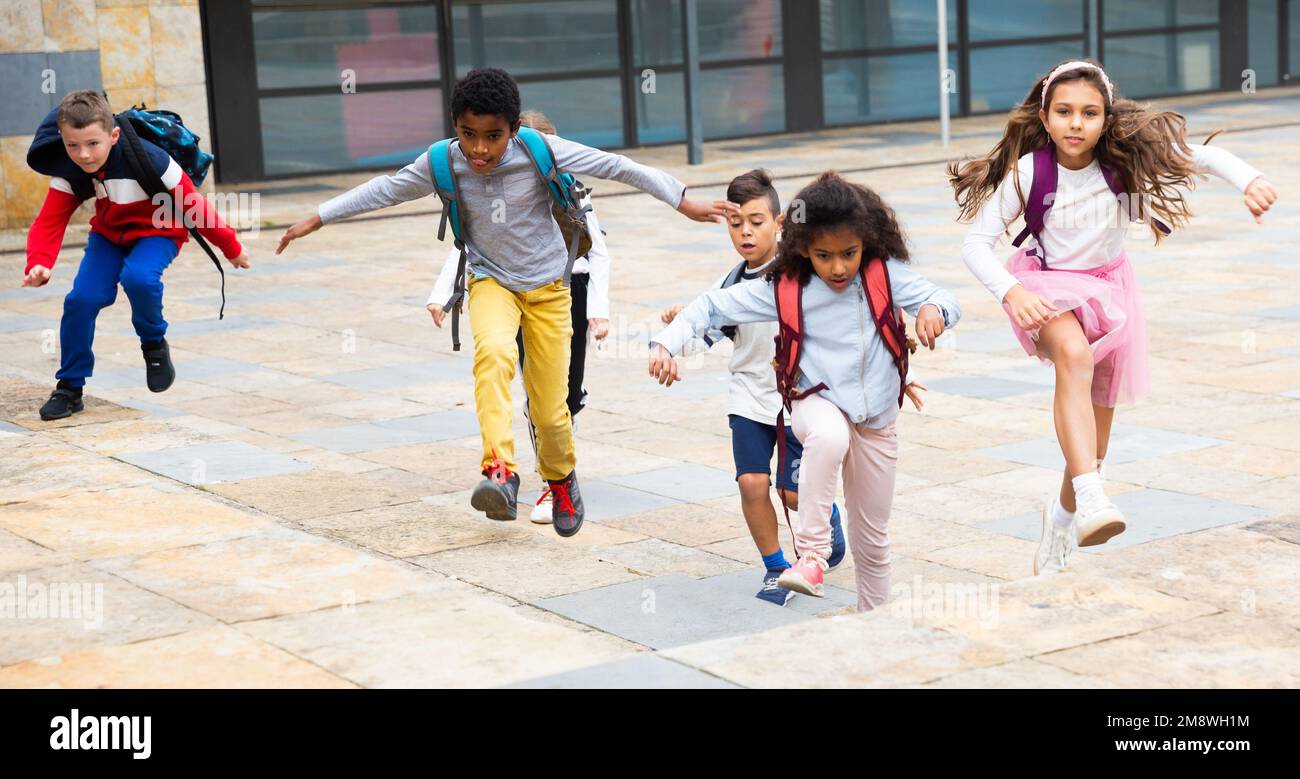 Tween boys and girls with school backpacks running in schoolyard Stock ...
