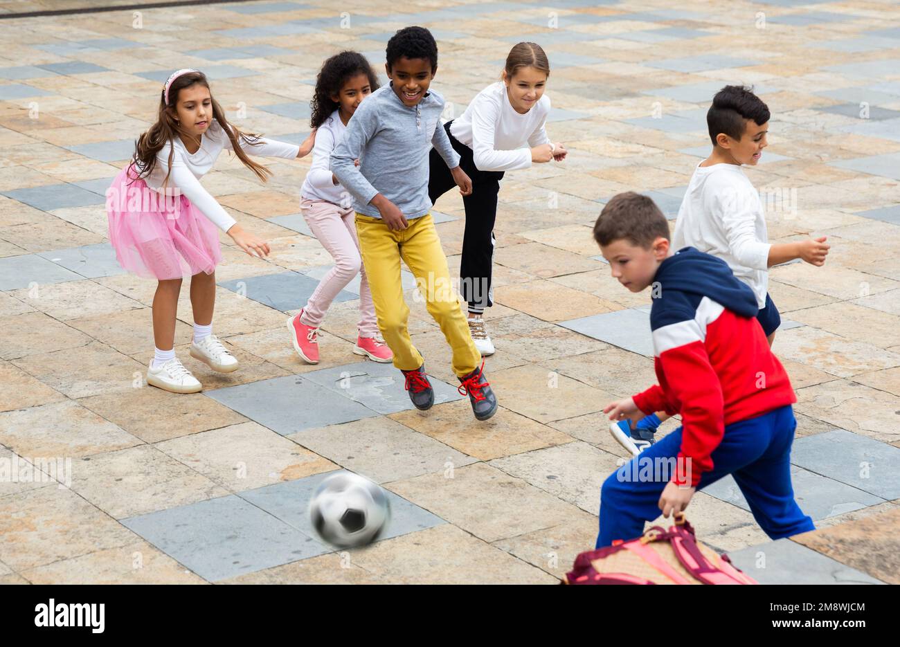 Cheerful tween schoolchildren playing with ball near school Stock Photo ...