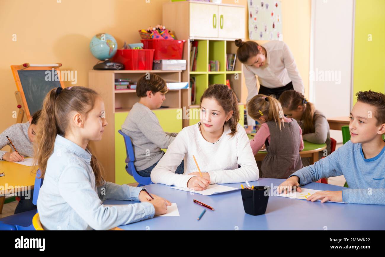 Kids studying and teacher helping Stock Photo - Alamy