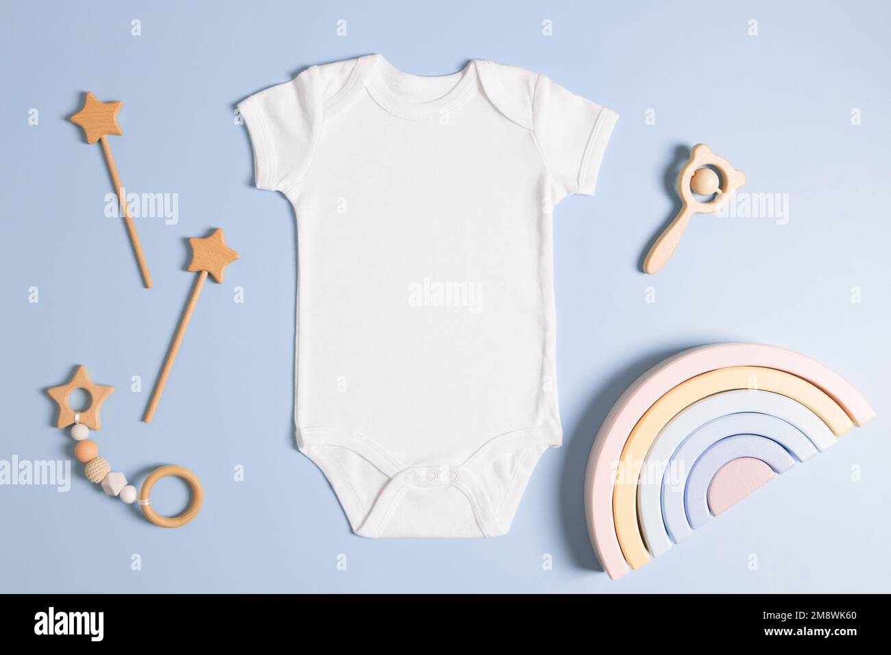 White cotton baby short sleeve bodysuit and natural wooden toys on ...