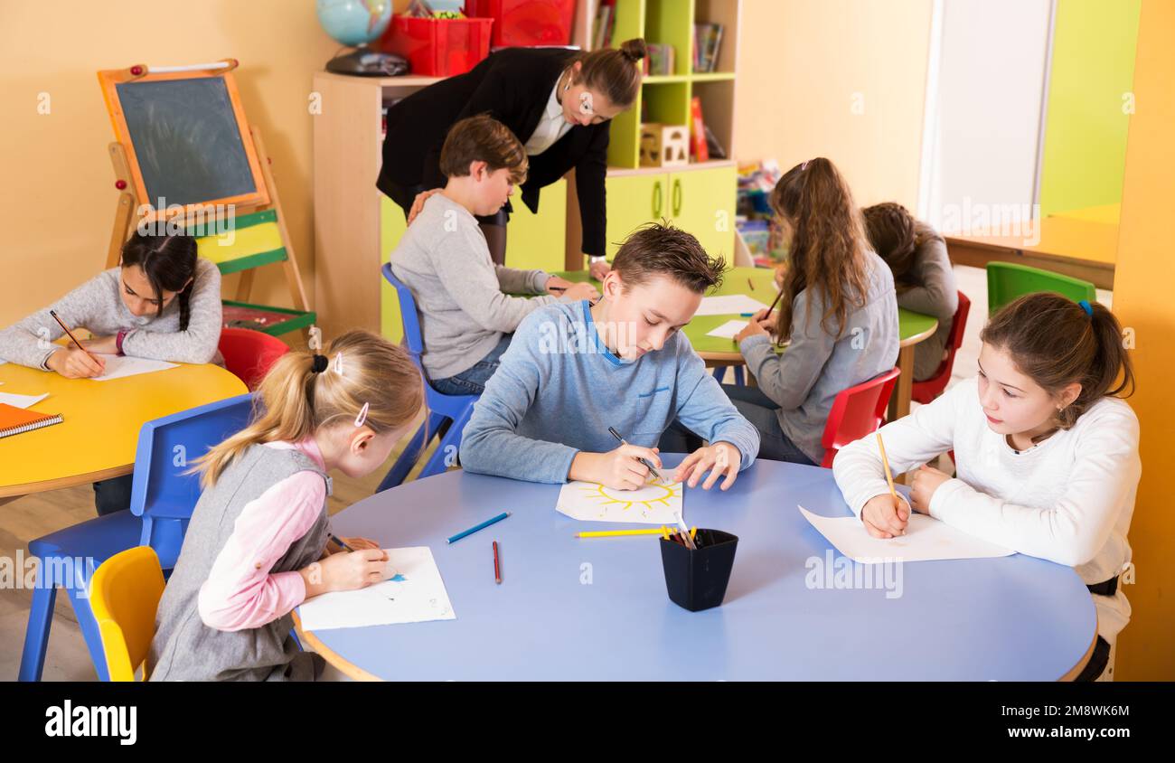 Kids studying and teacher helping Stock Photo - Alamy