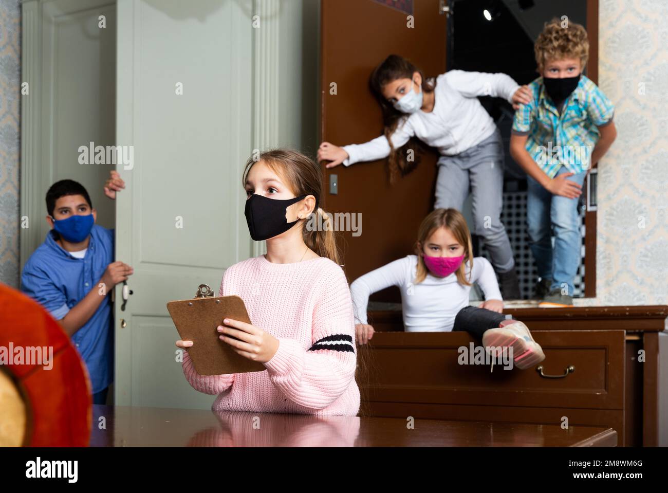 Tween girl in protective mask reading task in quest room Stock Photo ...