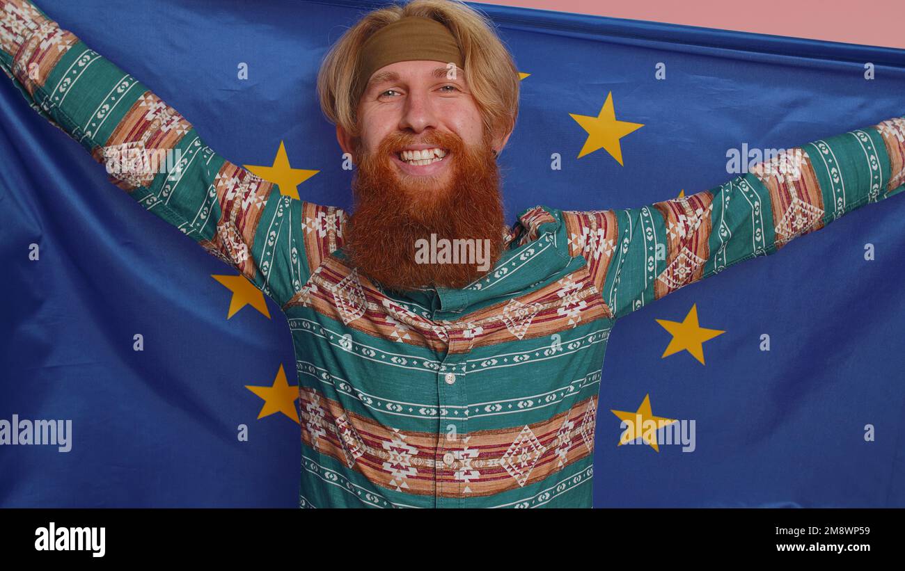 Hippie redhead bearded man in pattern shirt waving European Union flag ...