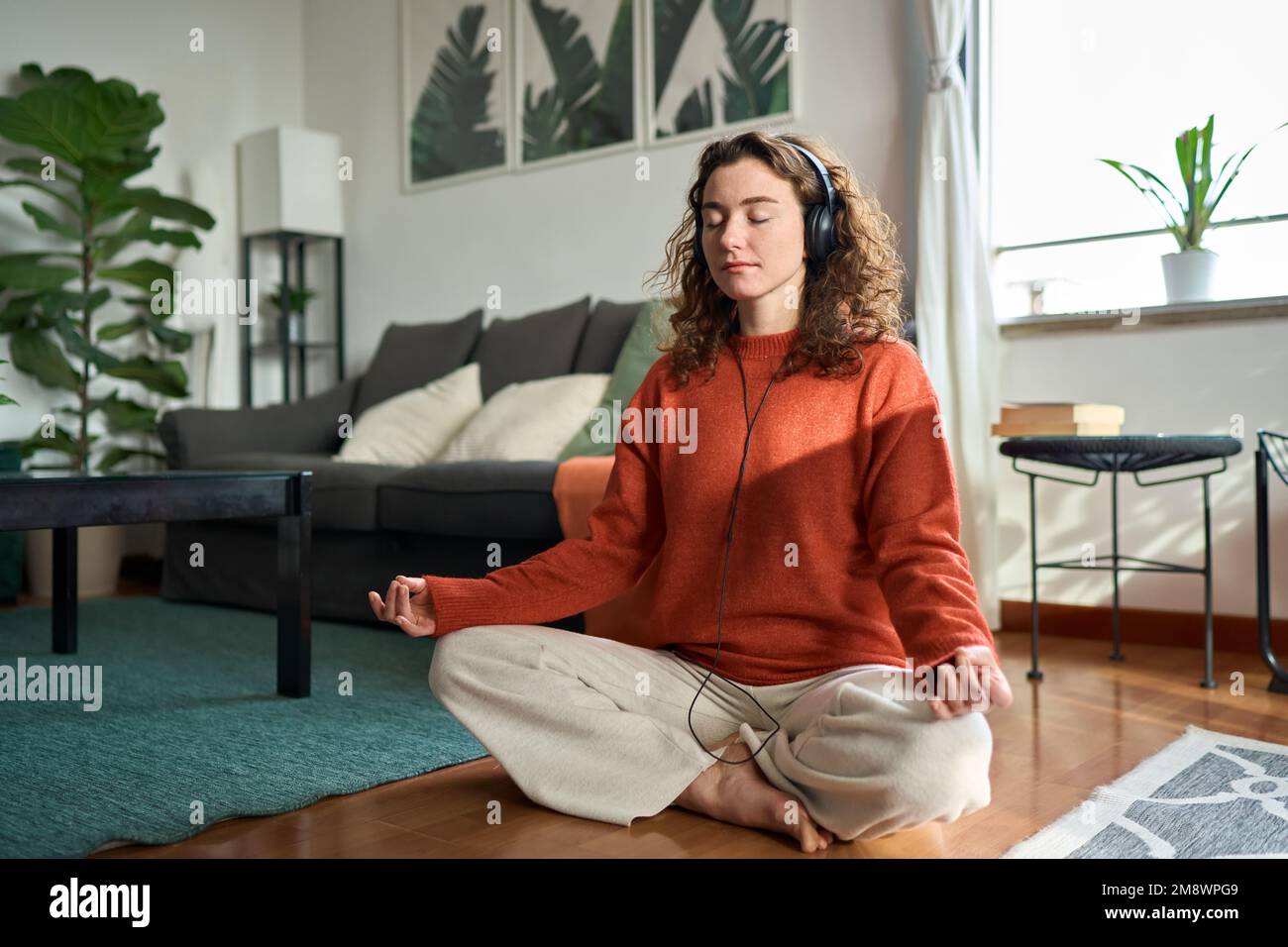 Young mindful woman wearing headphones listening music doing meditation ...