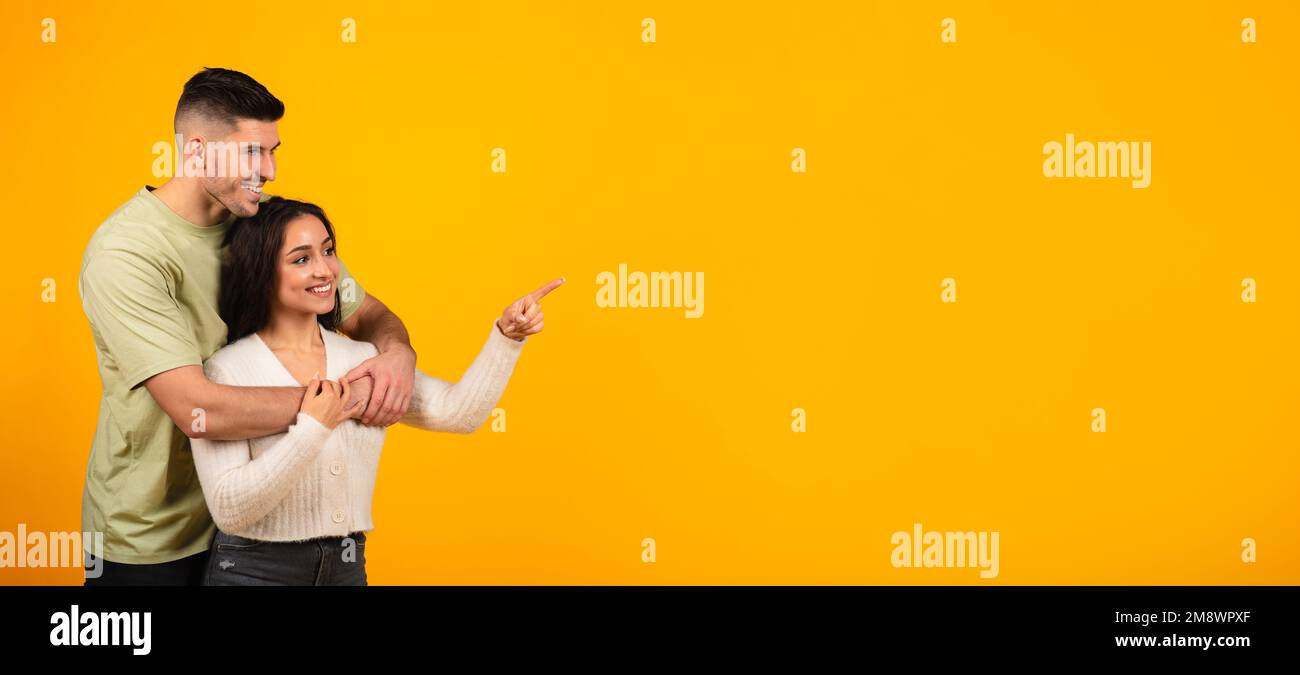 Smiling millennial arab male hug woman in casual, pointing finger at ...
