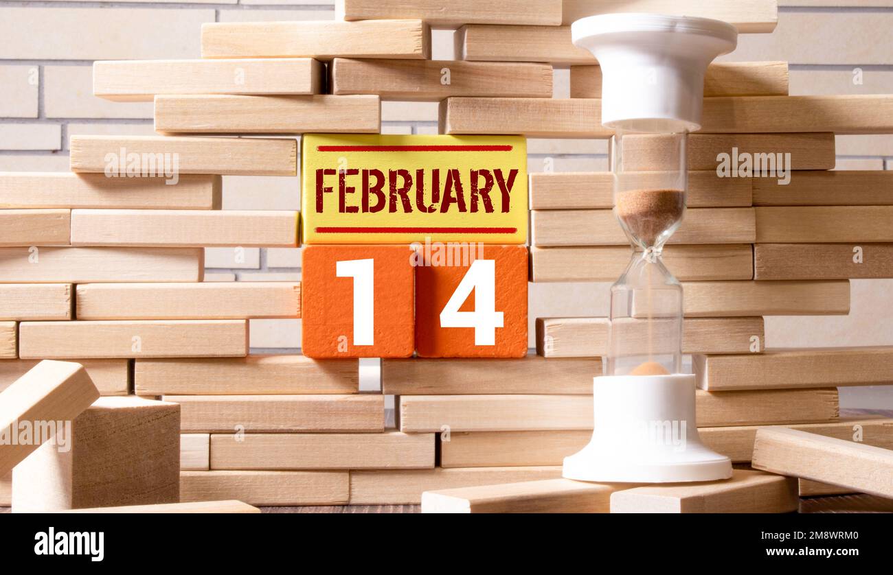 February 14 text on wooden blocks background. With green color ...