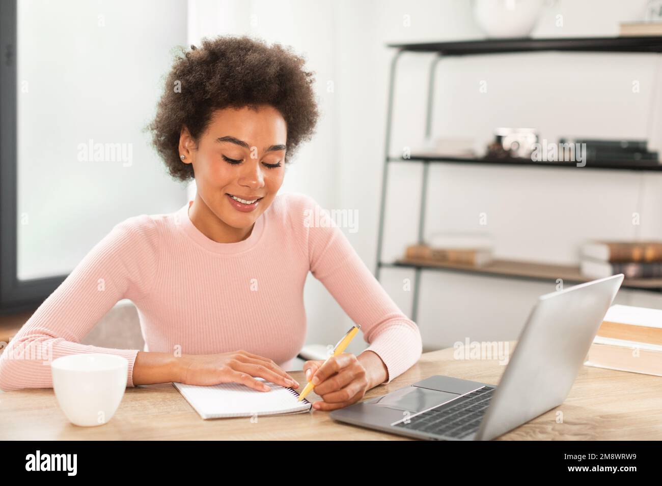 Cheerful pretty young mixed race curly woman manager making notes at ...