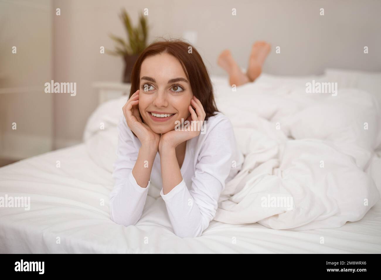 Well-rested young brunette enjoying happy morning, posing in bed Stock ...
