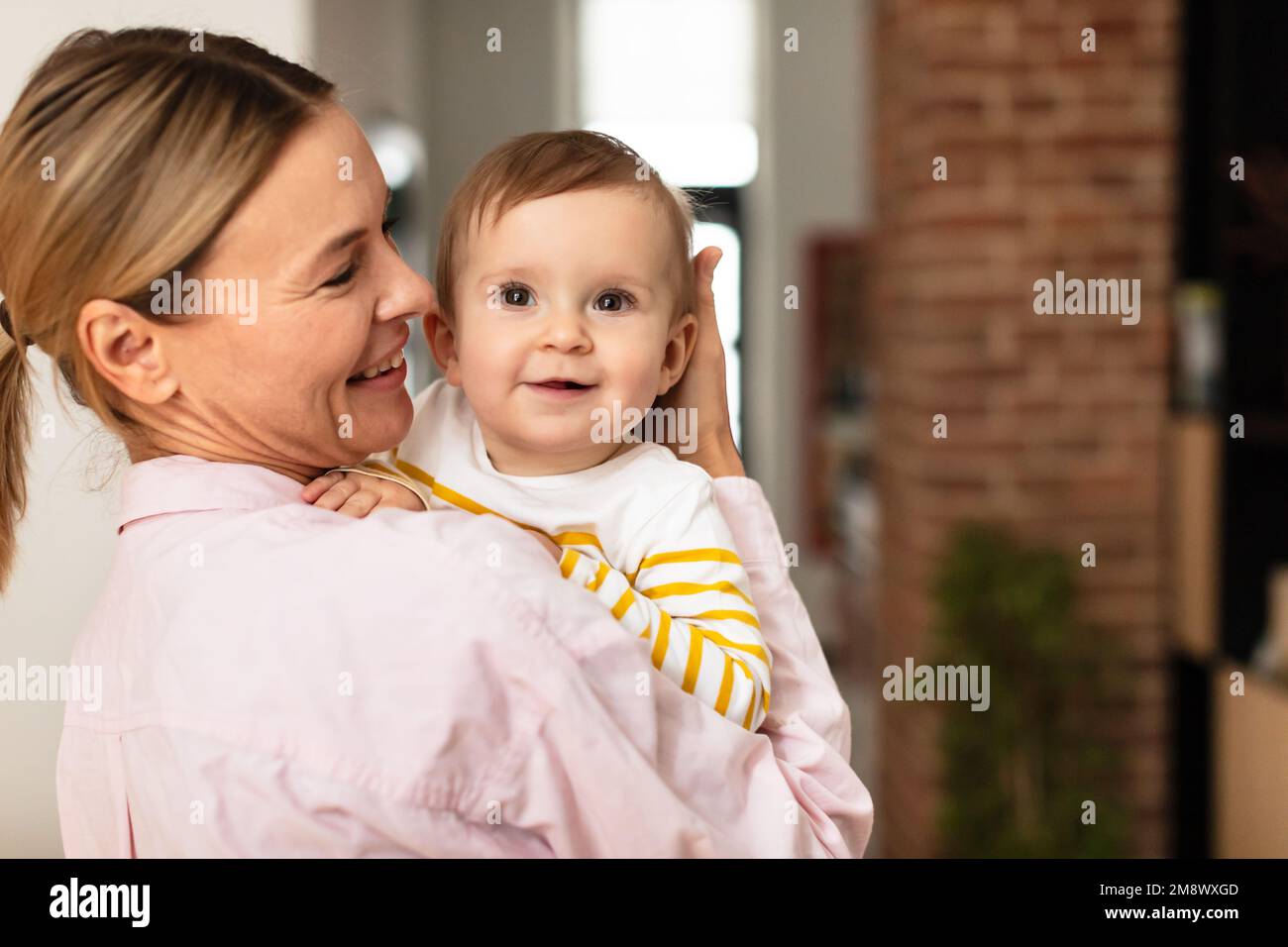 Maternal love. Mother holding cute infant girl on hands and cudding, embracing baby and smiling ...