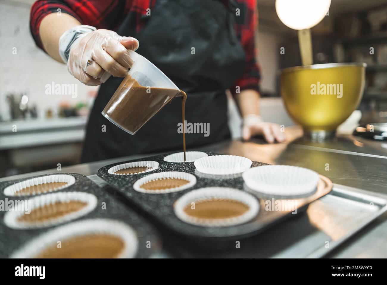 Female professional baker wearing black apron pouring out chocolate ...