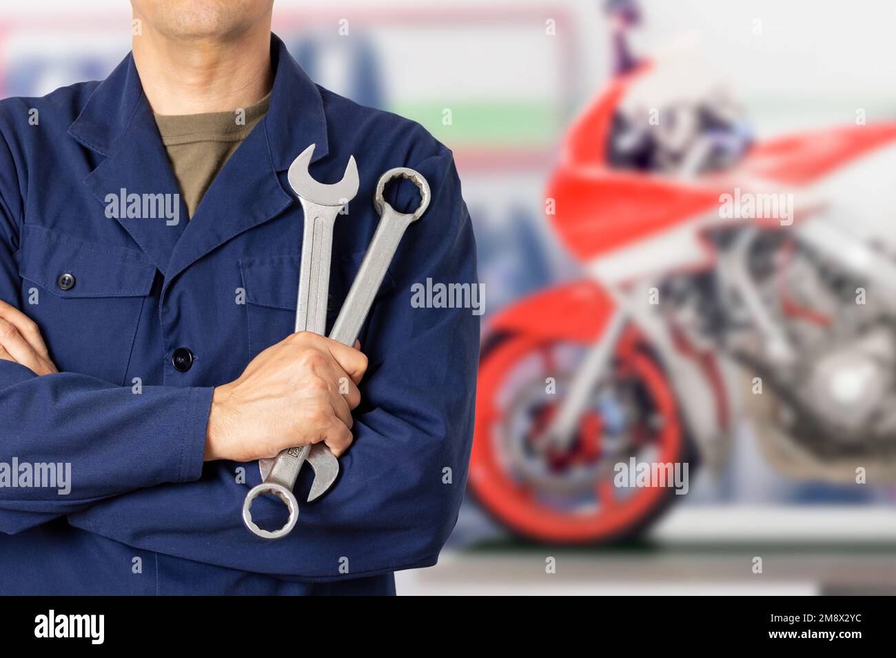 Motorcycle mechanic standing with workshop background with copy space ...