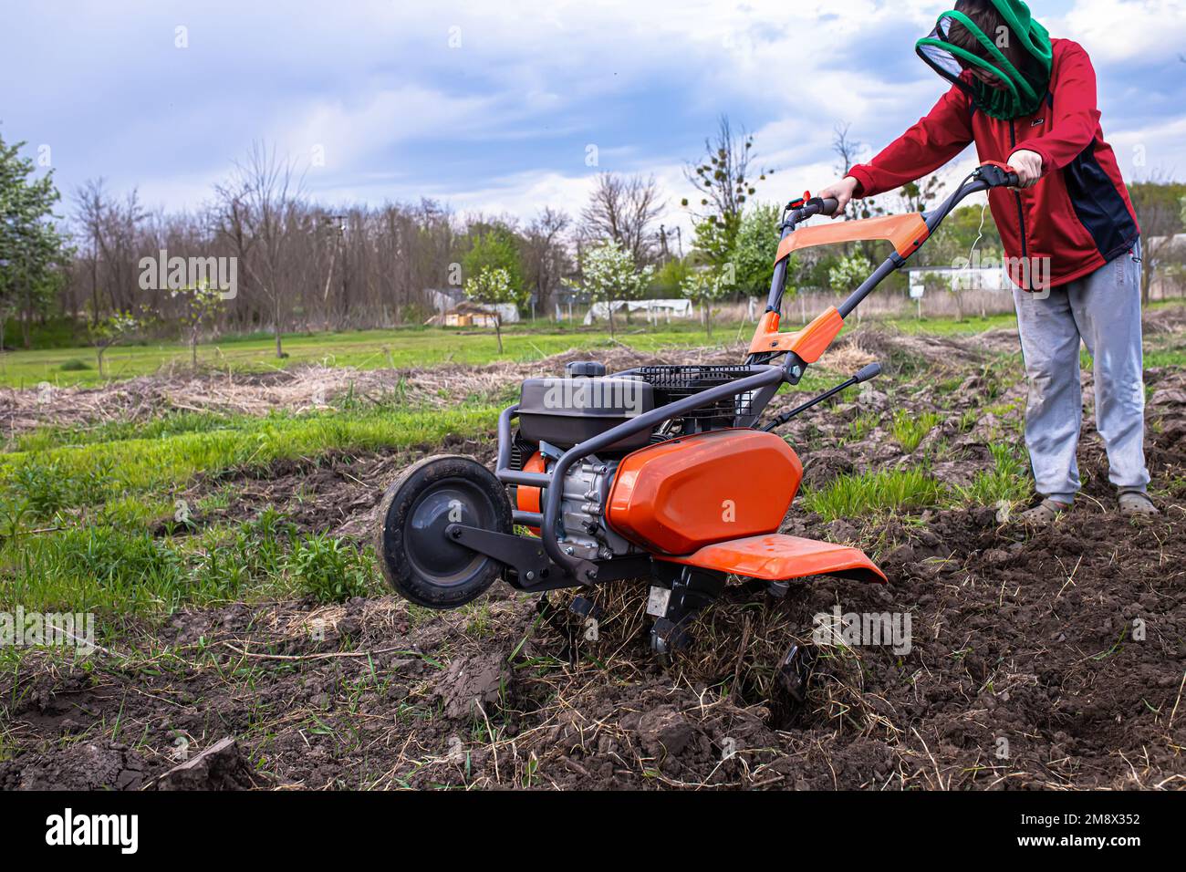 Work on the field of a home farm. Plowing the garden with a cultivator ...