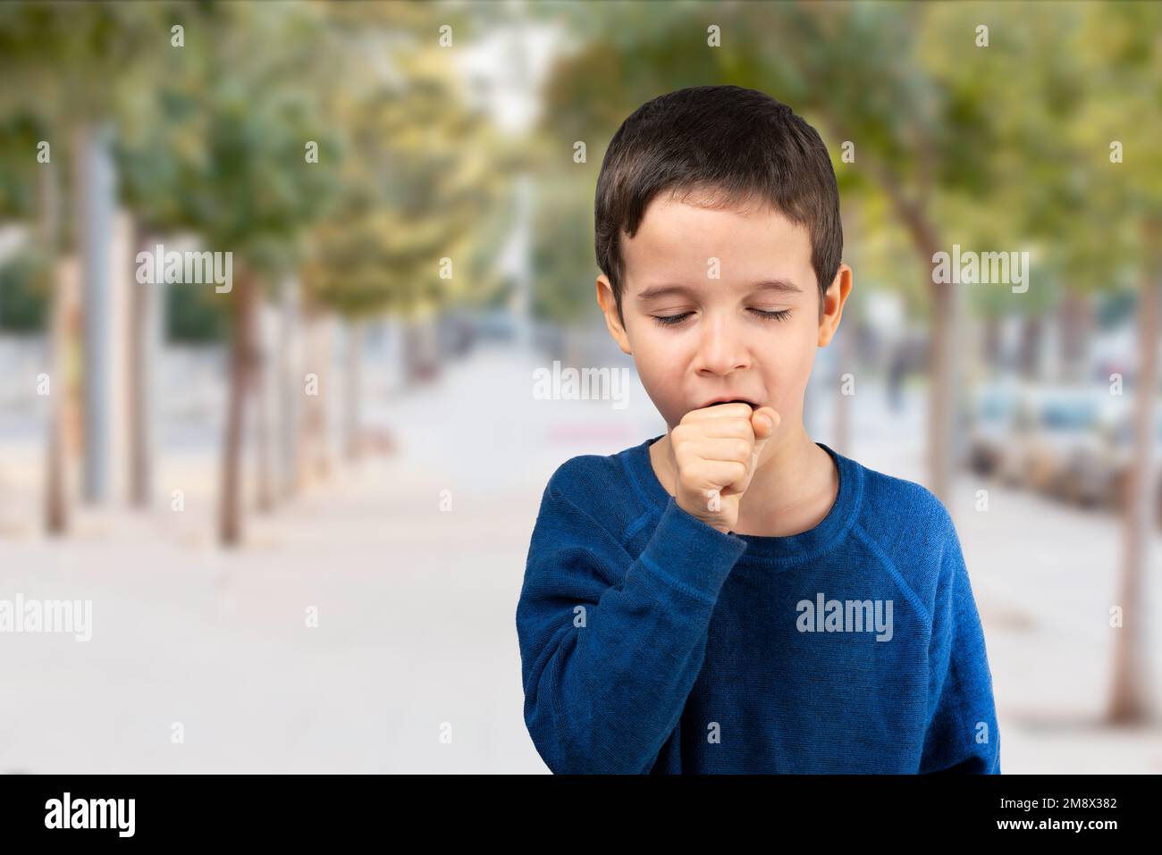 Kid wearing blue shirt walking down the street feeling unwell and ...