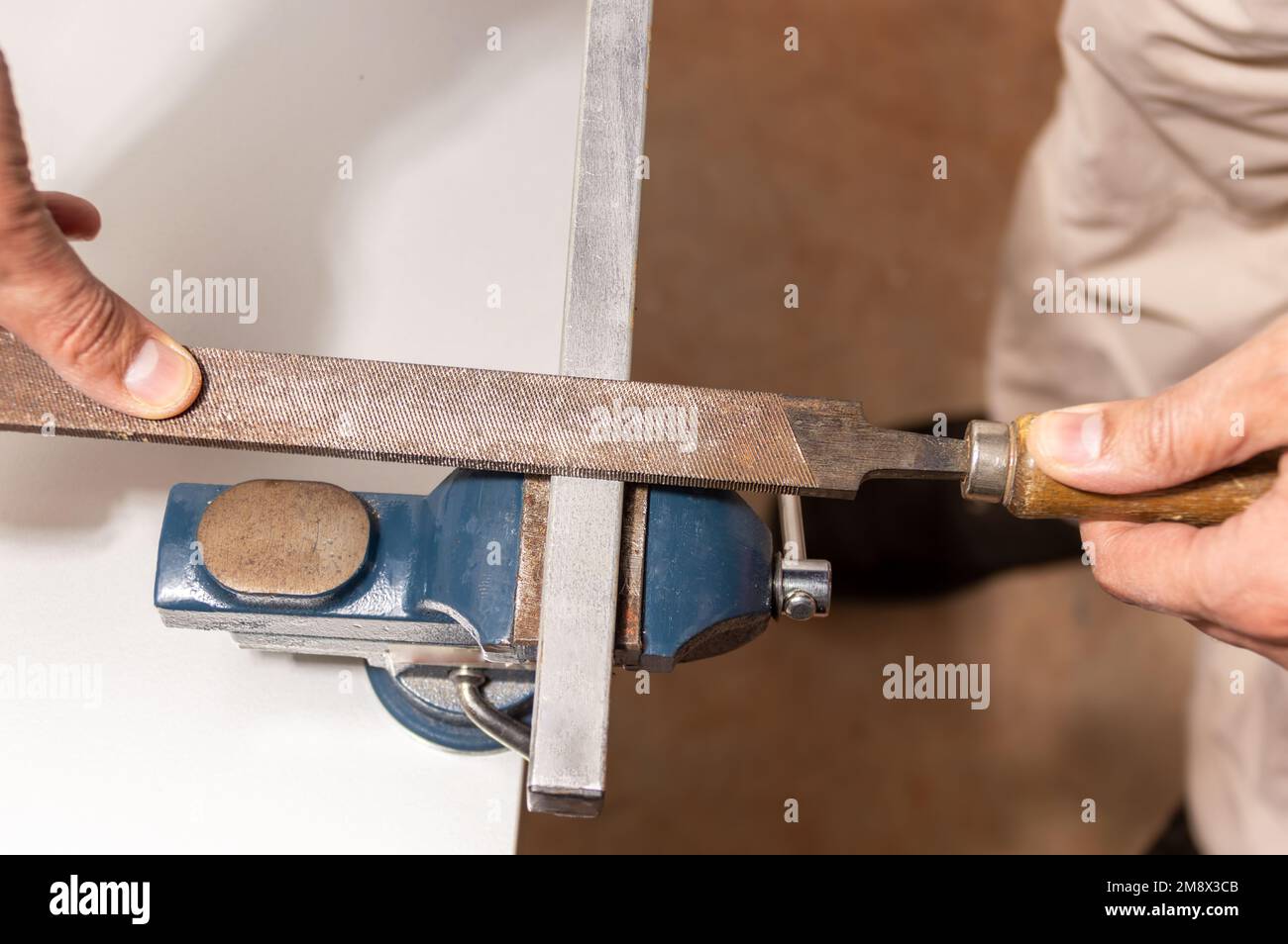 Man works with iron pipe or metallic aluminum file rasp gripped in vise ...