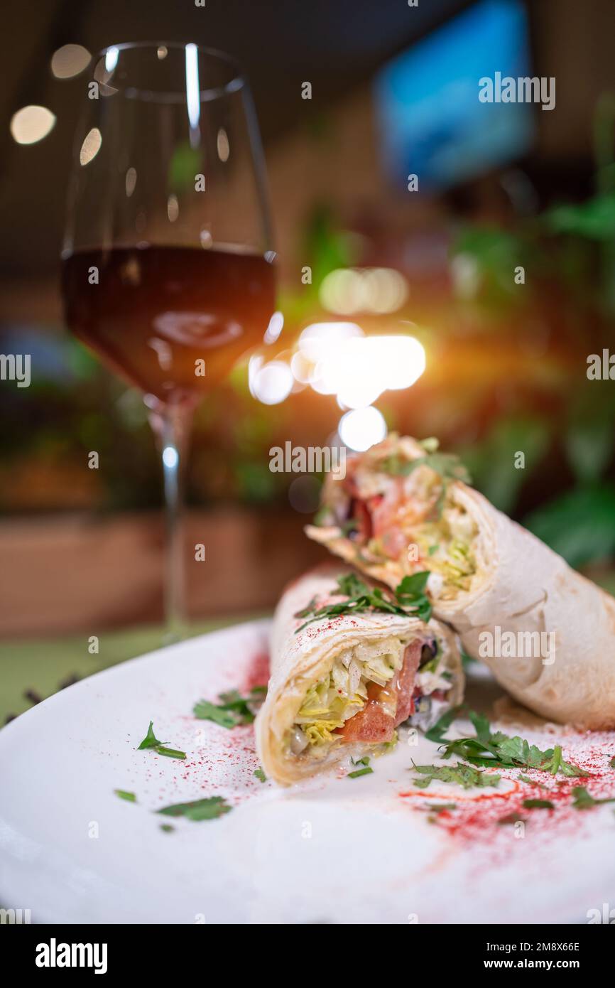 pita roll with chicken, tomato and cheese on white plate with sauce and ...
