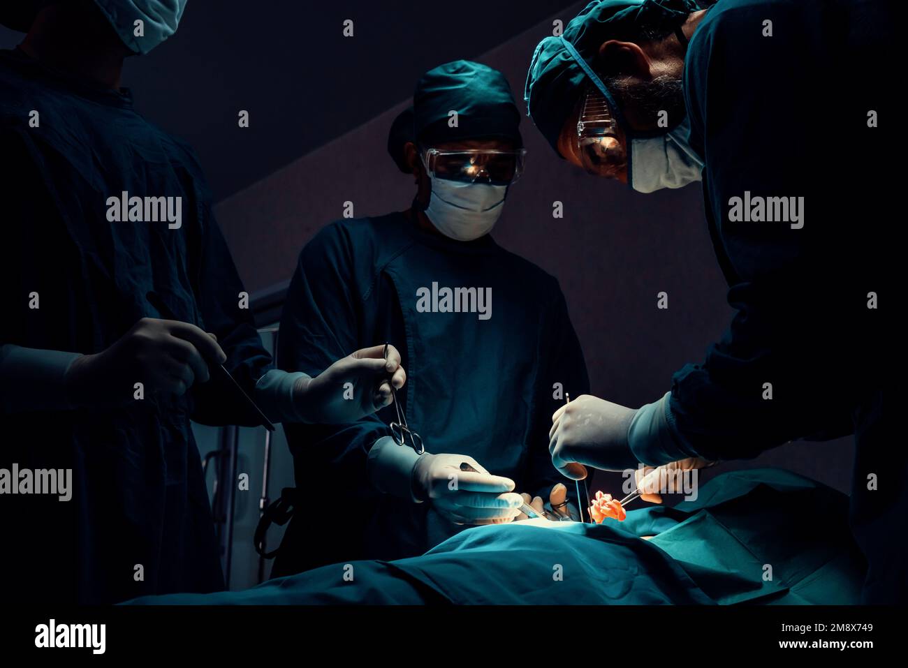 Surgical team performing surgery to patient in sterile operating room ...