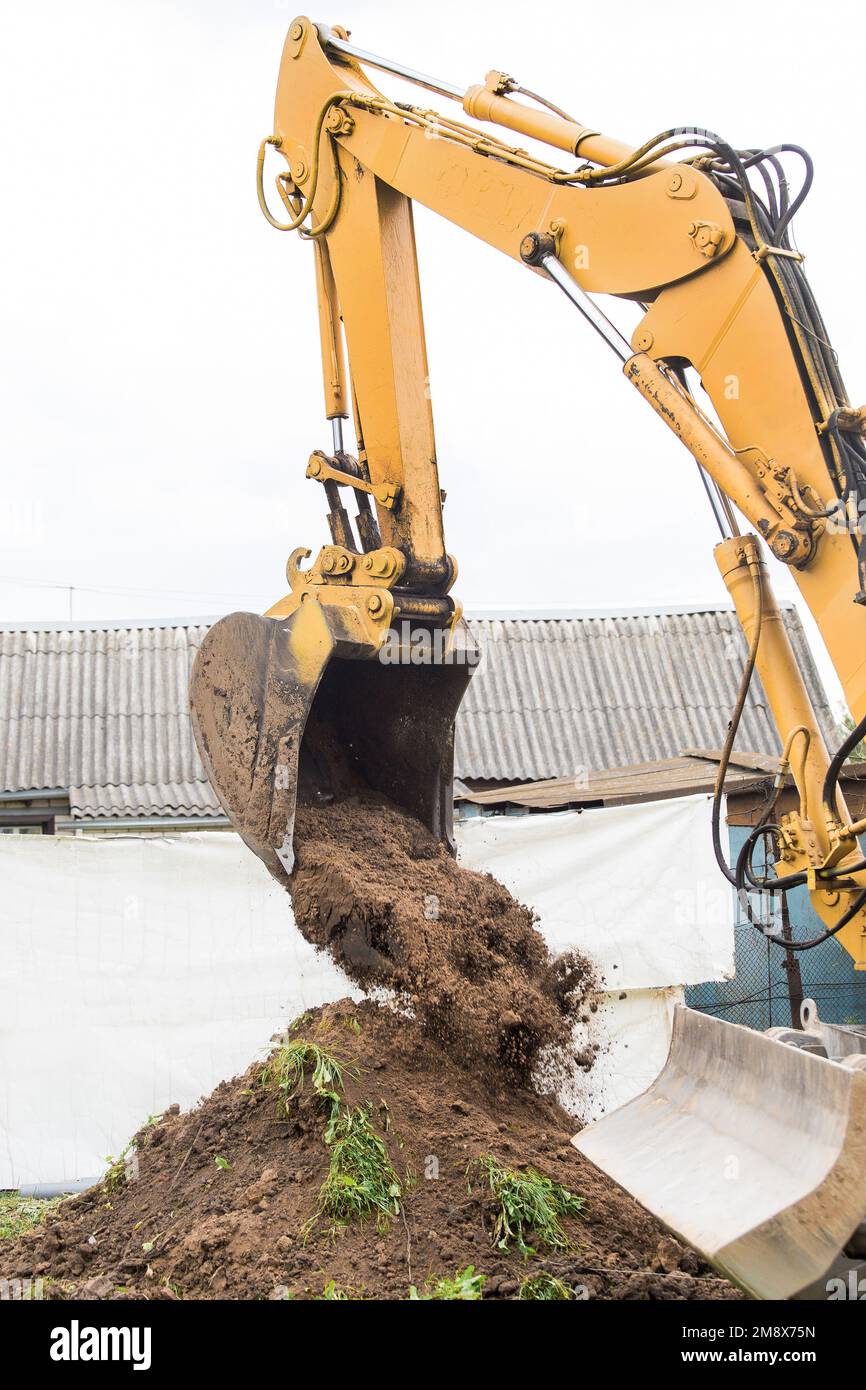 Excavation industrial work. A bulldozer pours out a bucket of land on a ...