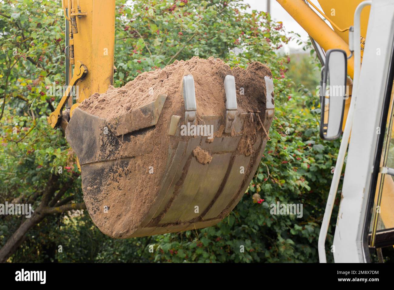 A bucket of excavator with a pile of land close-up. Excavation work in ...