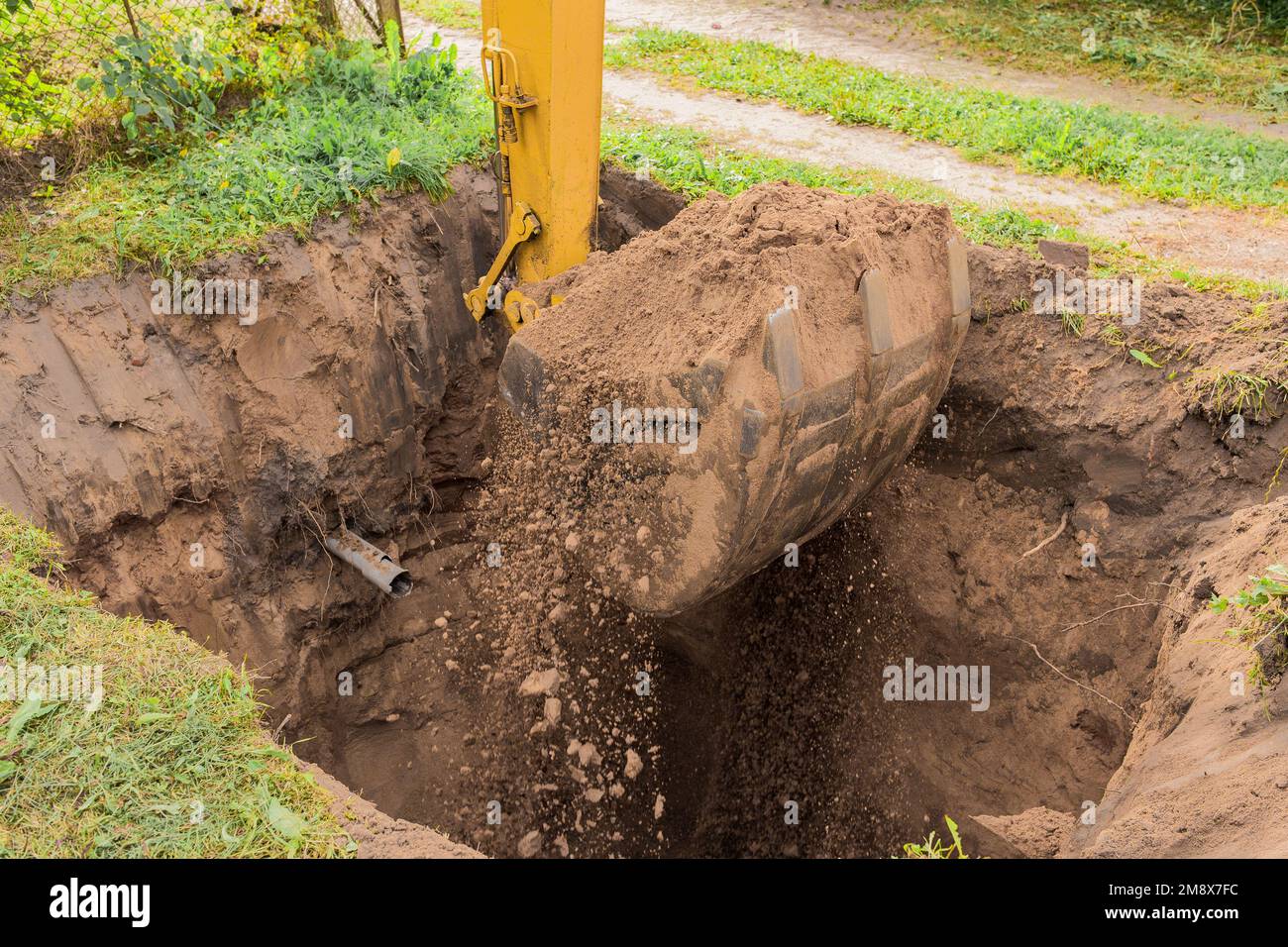 A bucket of excavator with a pile of earth digs a hole on the ...