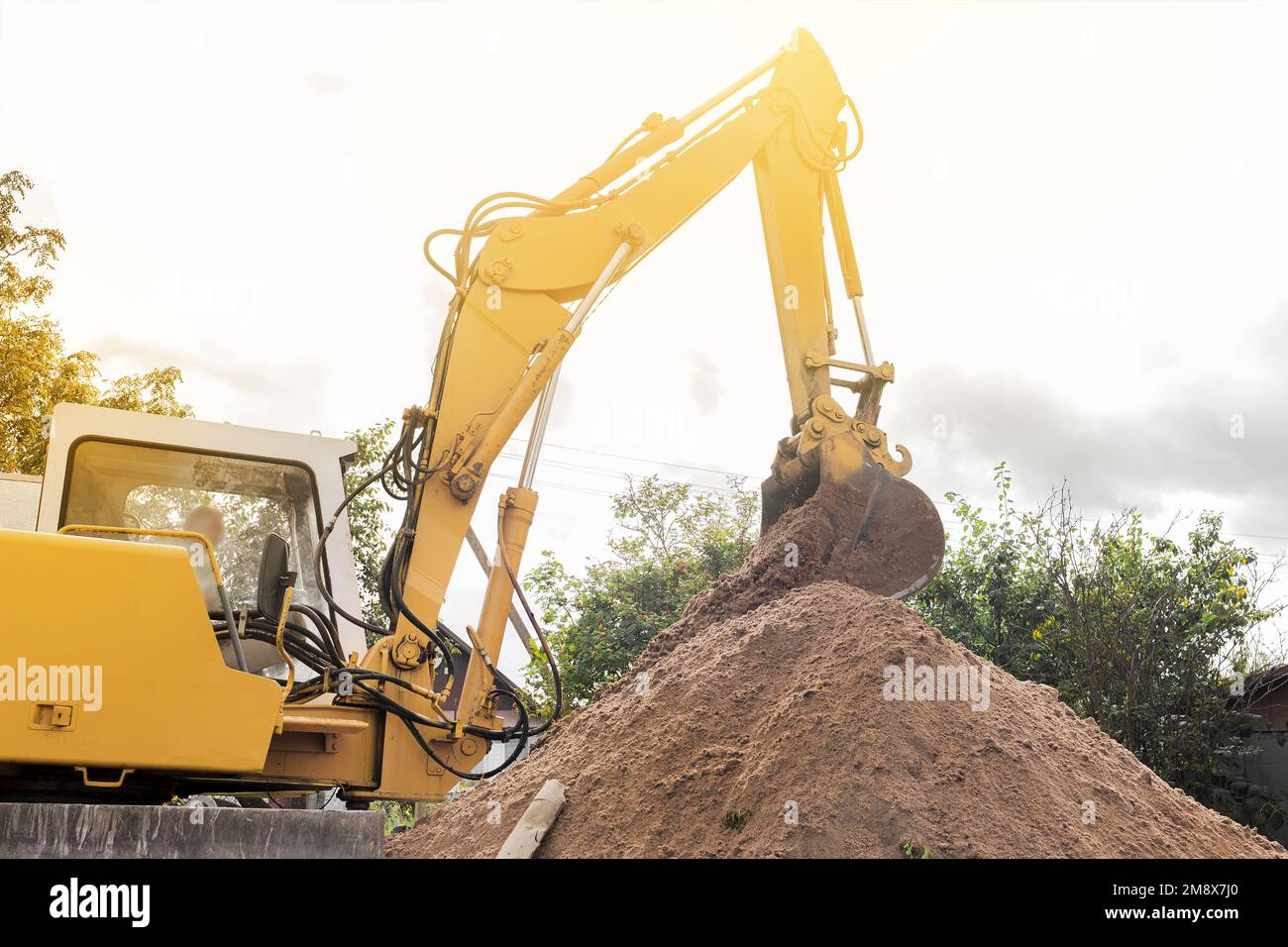 Hydraulic piston system excavator with a bucket unloads a large pile of ...