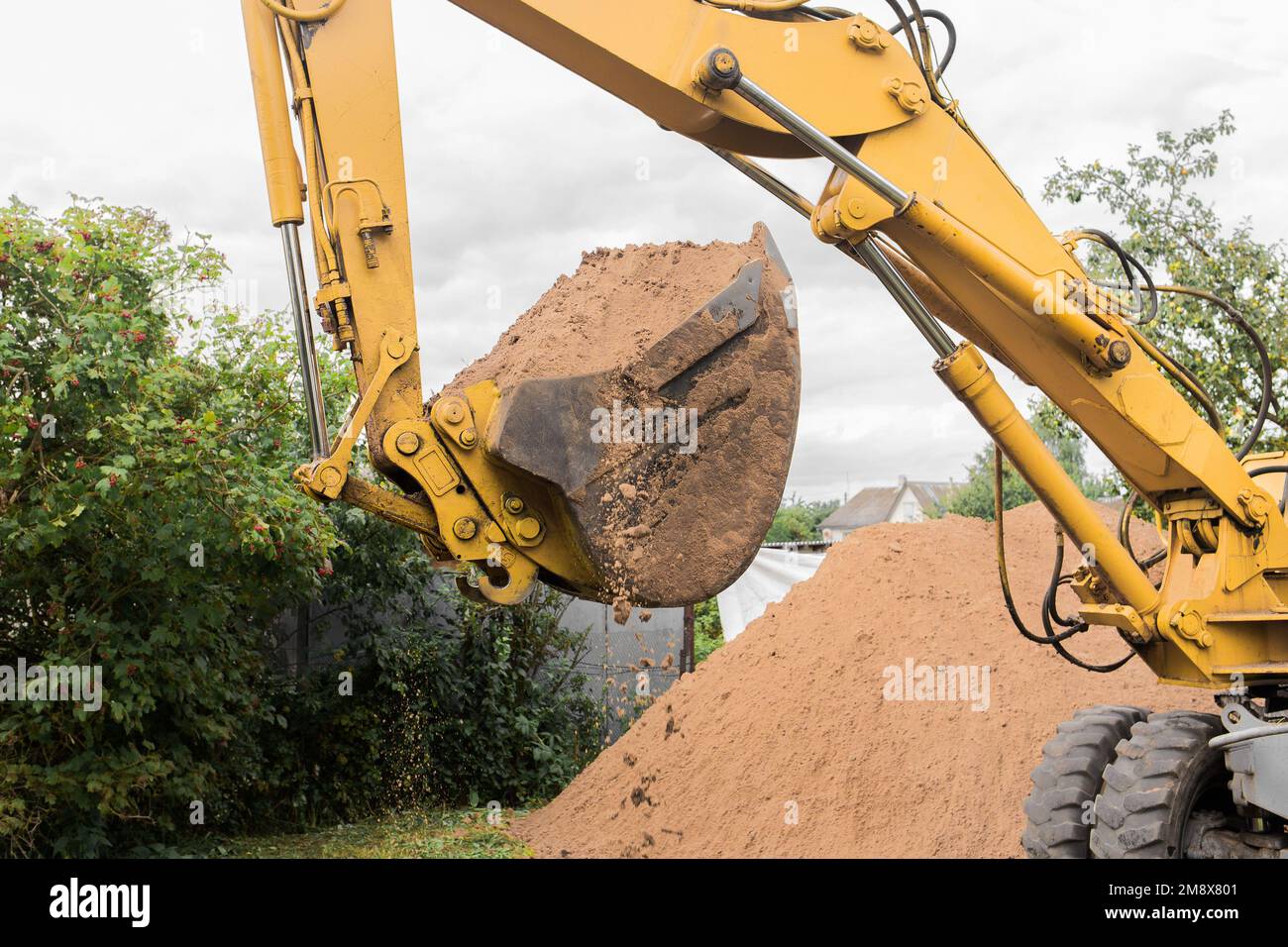 A bucket of excavator with a pile of sand and a ground background ...