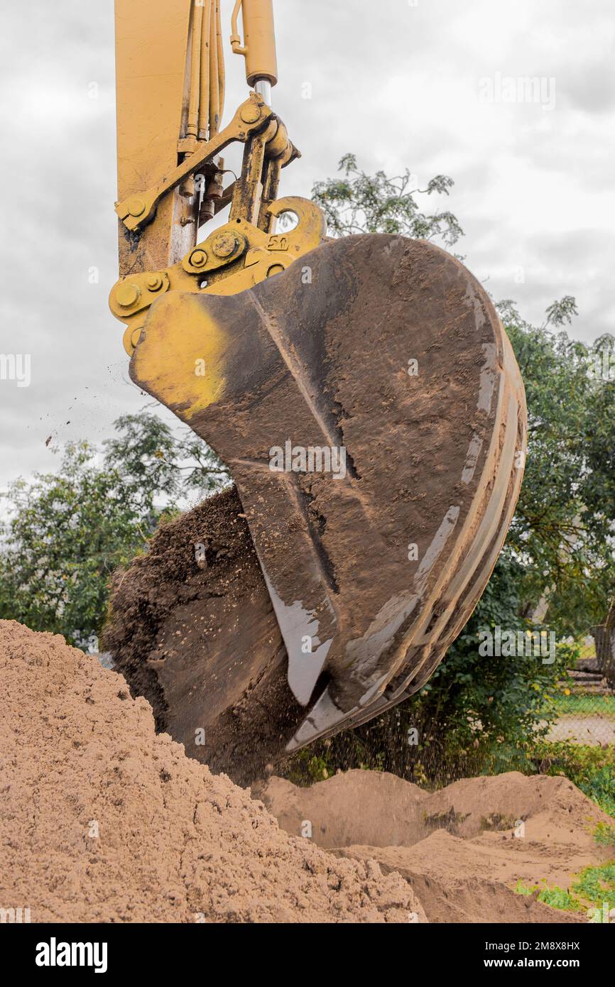 A bucket of excavator pours the ground into a heap against the ...