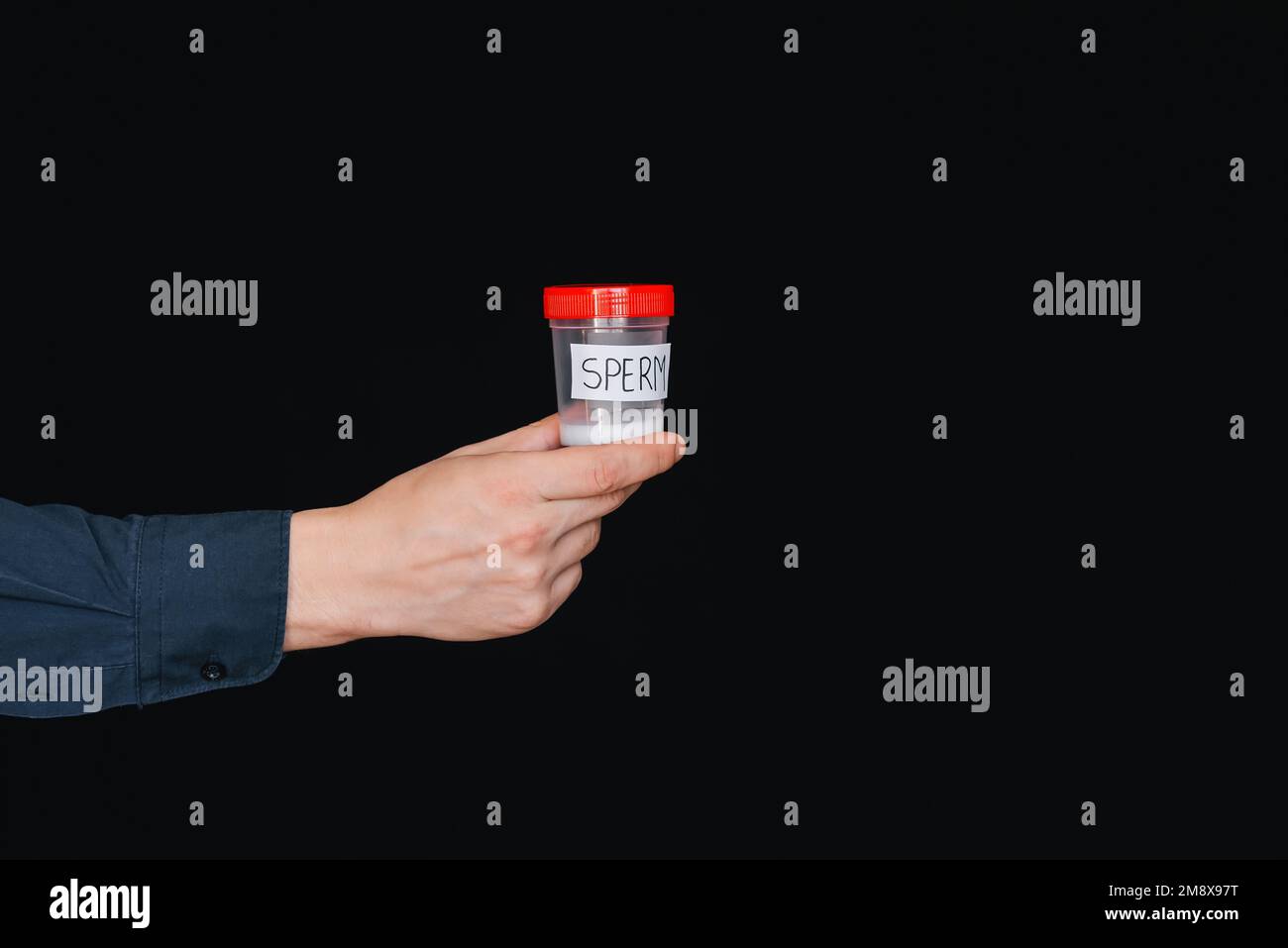 bank of sperm in a male donor hand for analysis on a black background ...