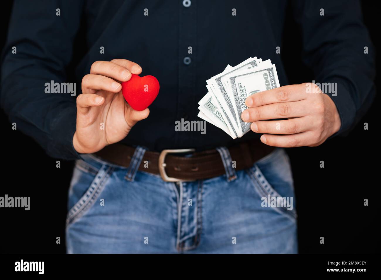 dollar bills and a red heart in the hands of a man. The concept of love ...