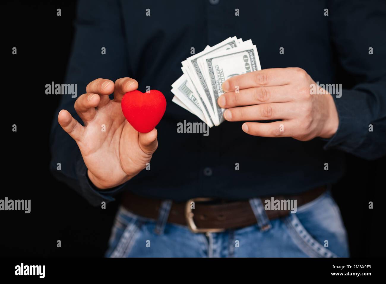 dollar bills and a red heart in the hands of a man. The concept of love ...