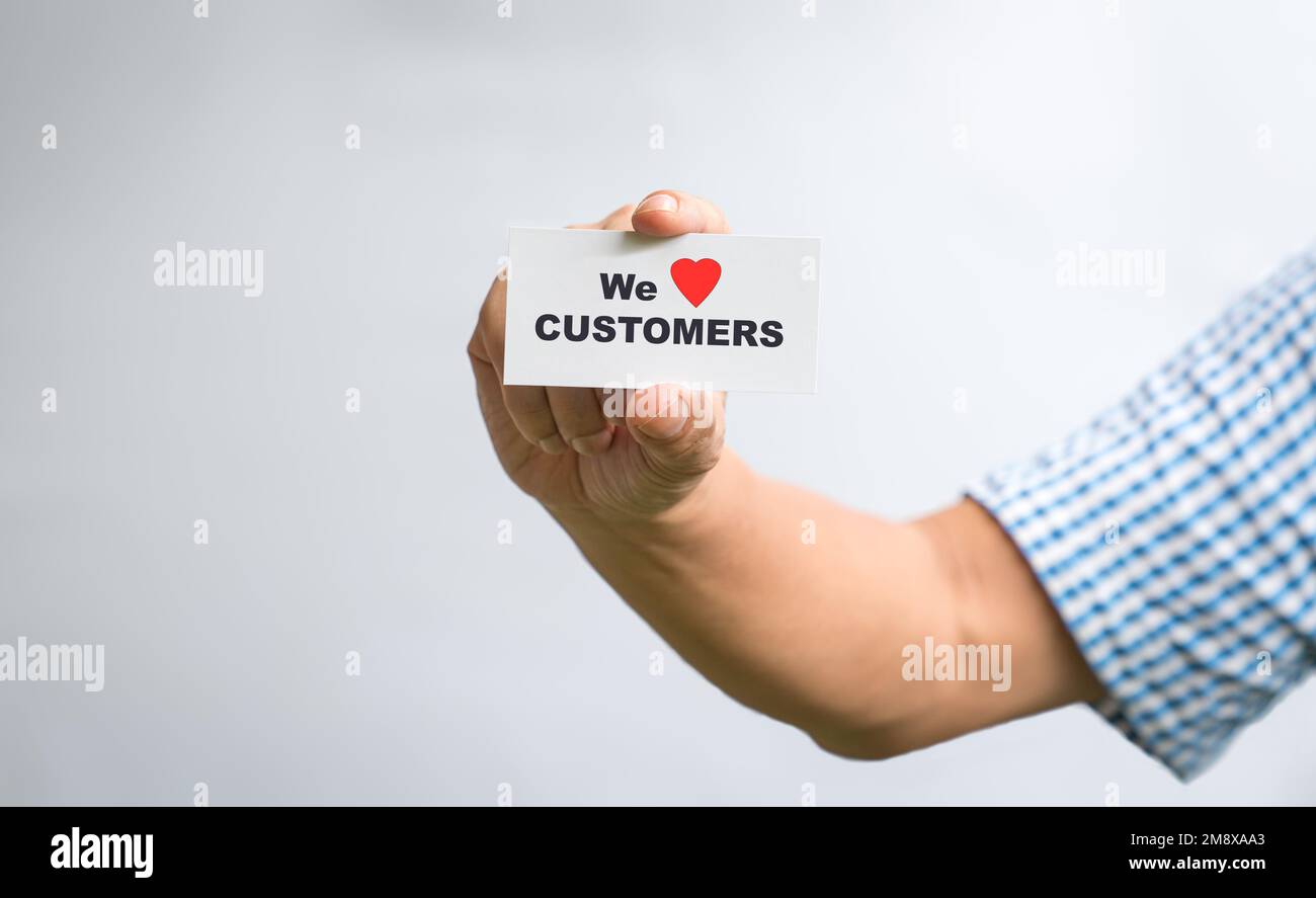 Man holding a white business card with text, We love customers Stock ...