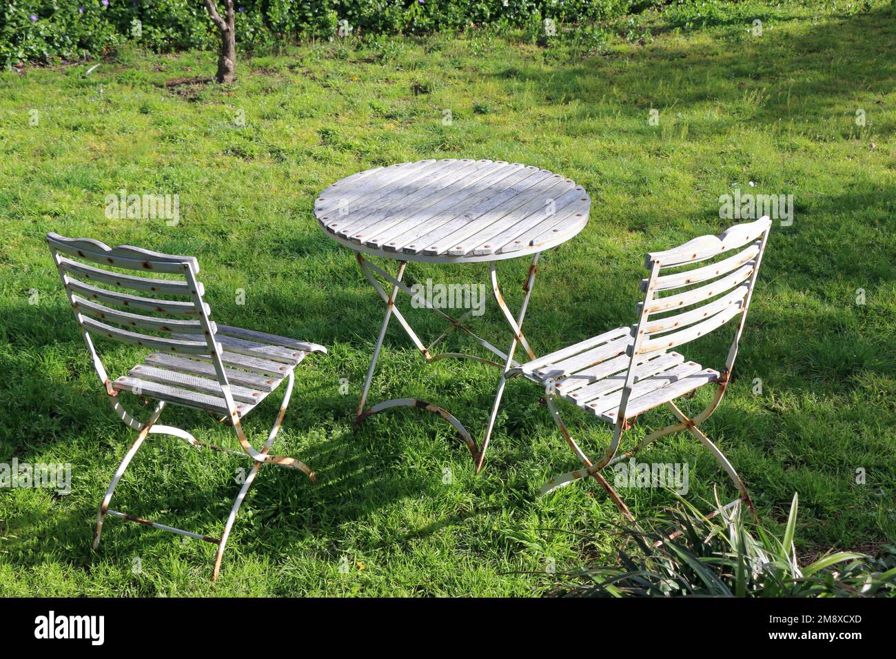 Weathered white table and chairs set in a lawn of deep green provide an ...