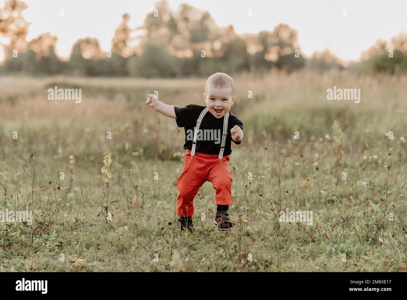 happy little baby boy running on summer grass. Added grain simulates ...