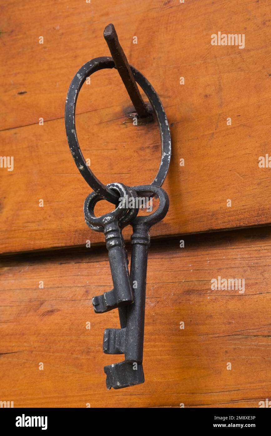 Set of old cast iron keys on ring hanging on exterior wall of squared ...
