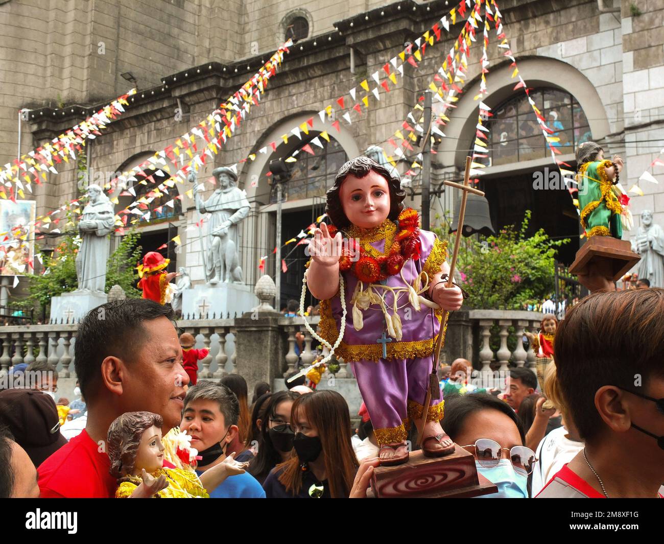 Devotees holding their Santo Niño while waiting for their turn to enter ...