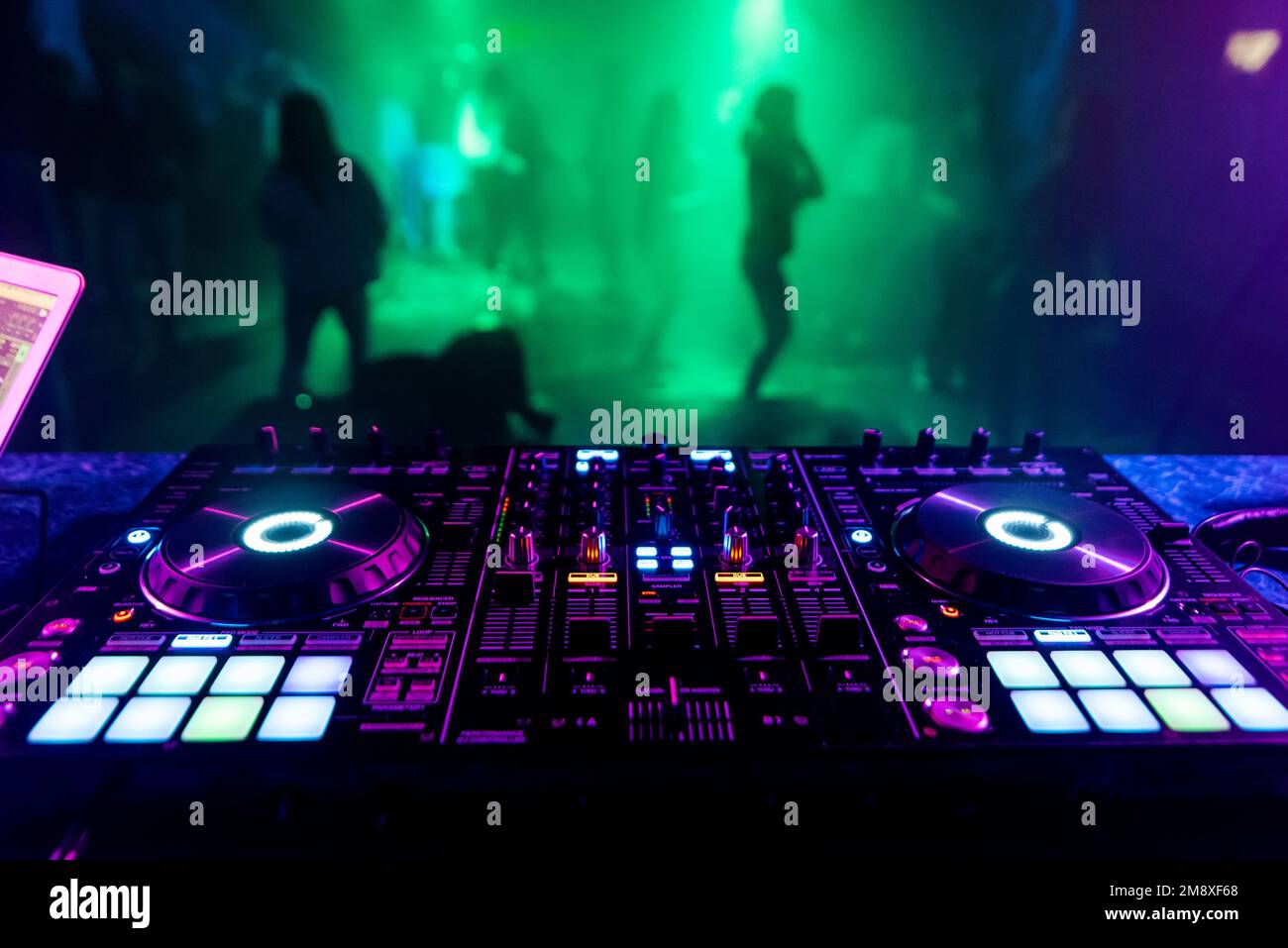 DJ mixer in the booth on the background of the dance floor with dancing ...