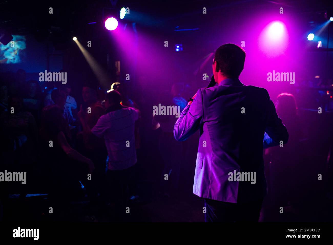 artist with a microphone performs on the stage of a nightclub at a ...