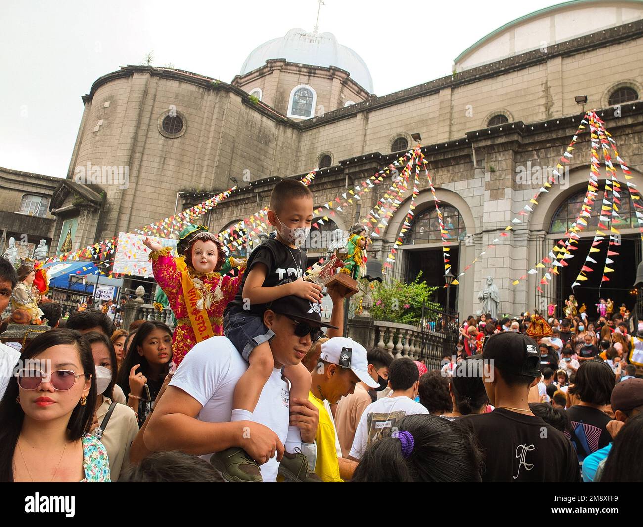 Manila, Philippines. 15th Jan, 2023. A father carries his son on his shoulder as they leave ...