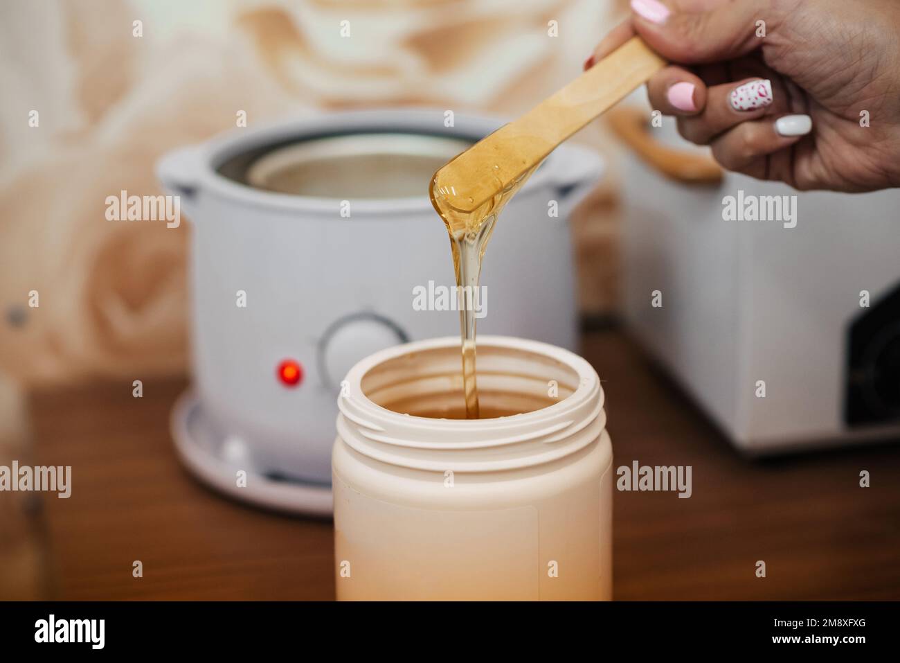 natural hot sugar paste for depilation in a jar and on a wooden spatula ...