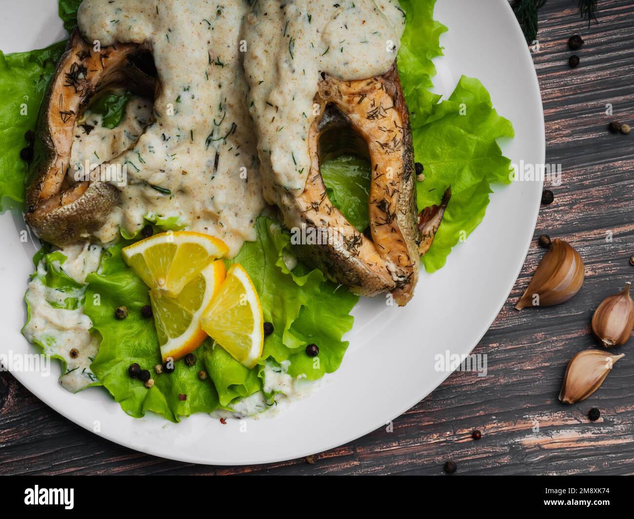 fried red fish in cream sauce with lemon. Pieces of trout on a plate in ...