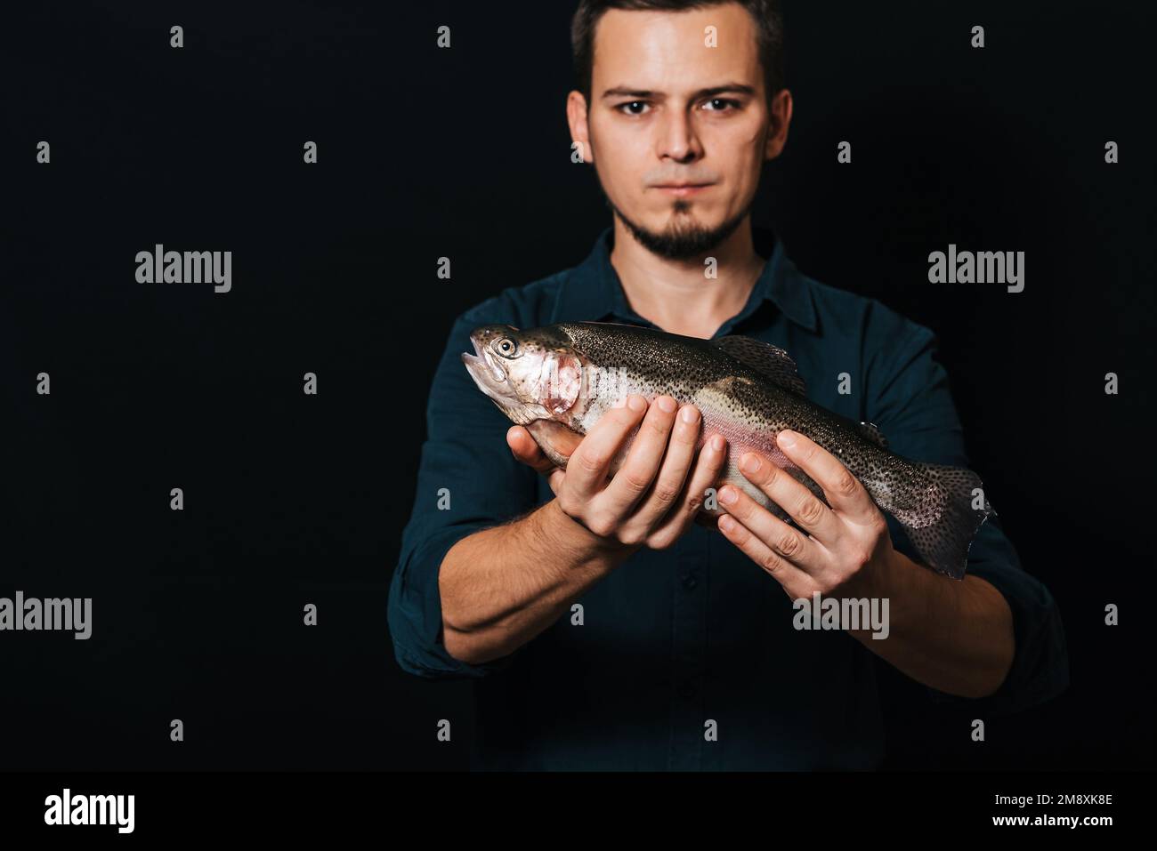 Red fish. man of Caucasian appearance holding a trout in the Studio on ...