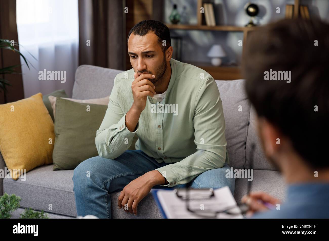 Visiting a psychologist Afro-american man is sitting on the couch and ...