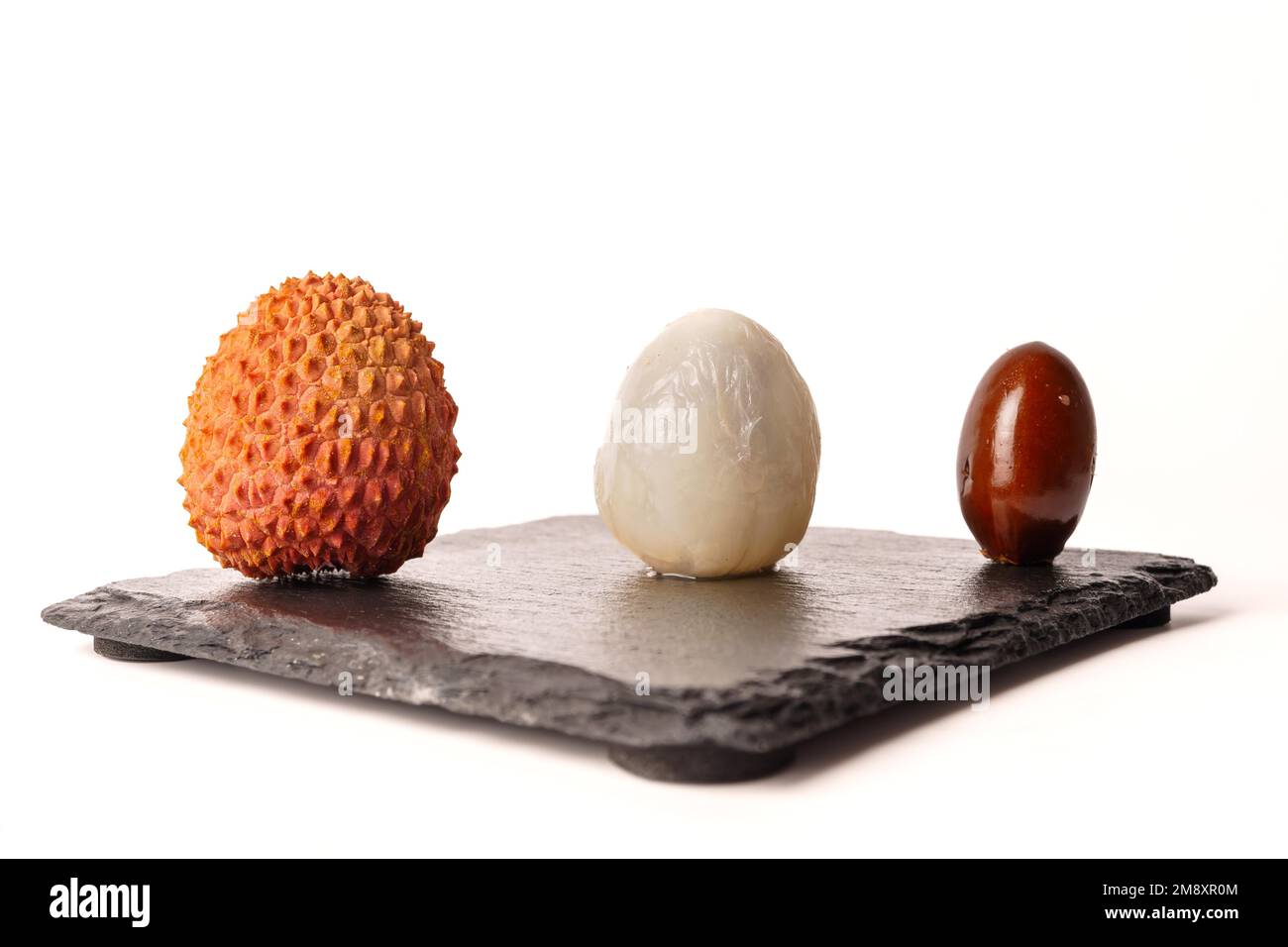 Whole fresh lychee, peeled and pitted on white background on a black ...
