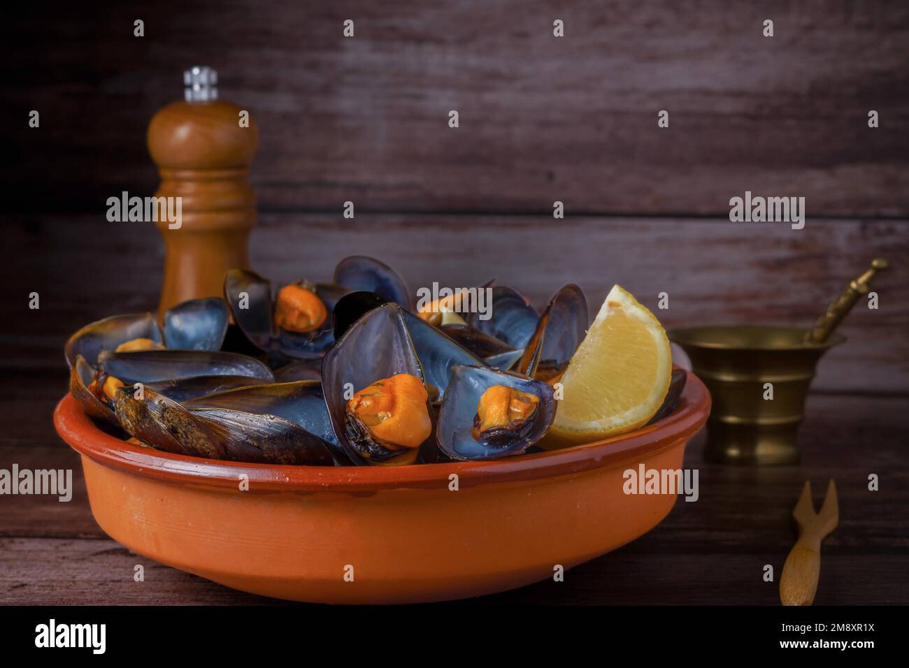Steamed mussels with lemon in clay pot with metal mortar and pepper ...